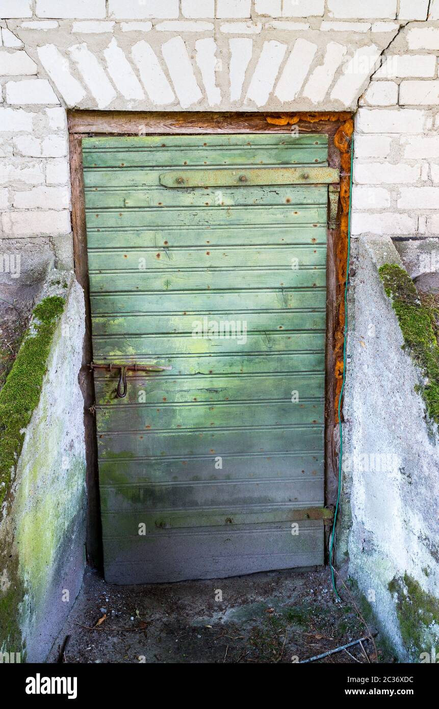 Old door leading to an underground basement Stock Photo - Alamy