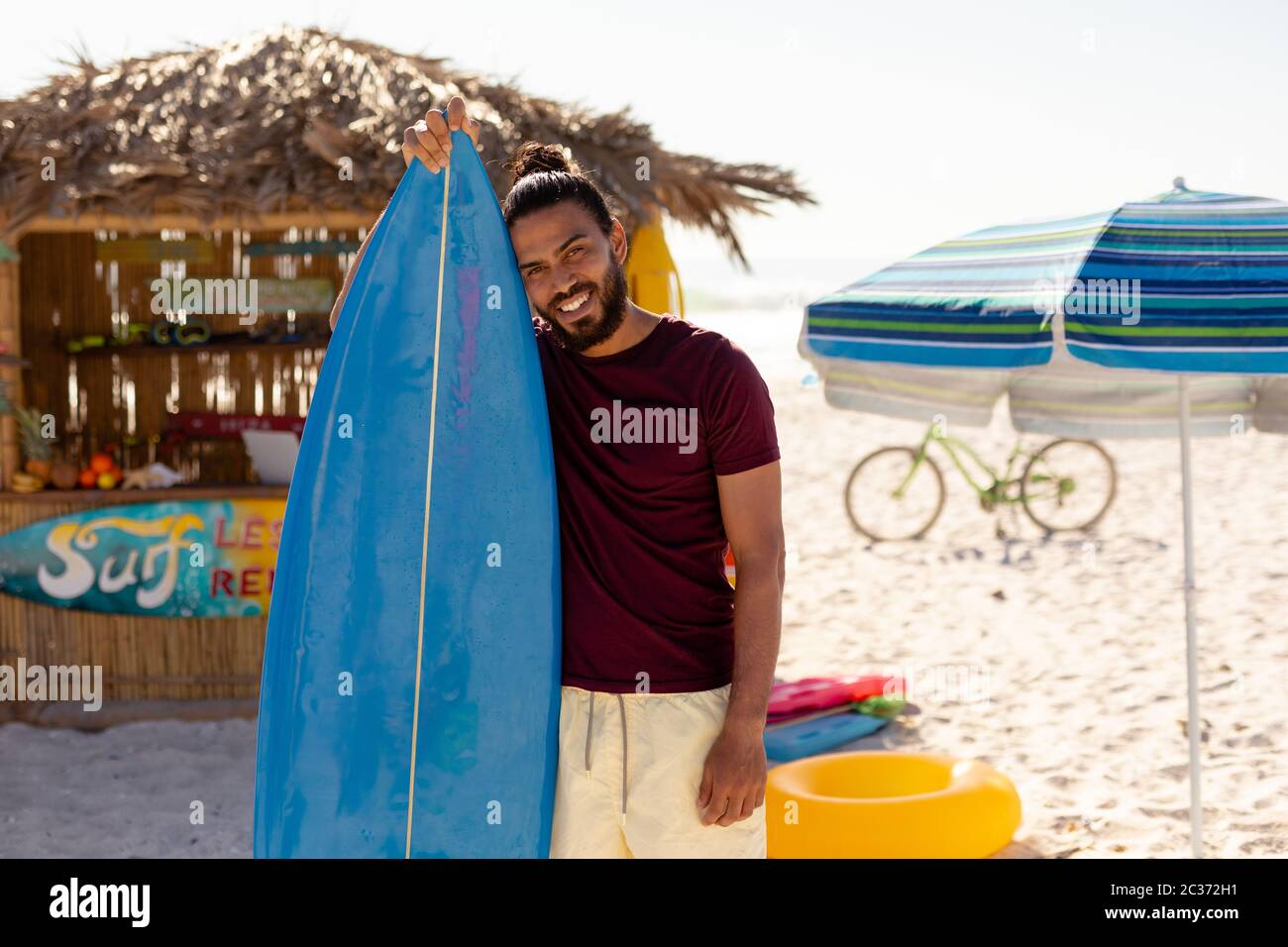 Mixed race man holding surf board on beach Stock Photo - Alamy