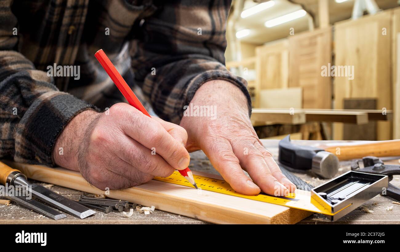 Close-up. Carpenter with pencil and carpenter's square draw the cutting ...