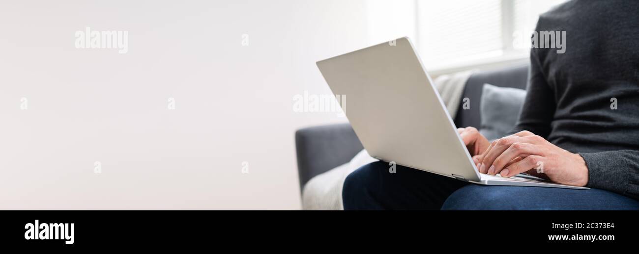 Relaxed Man Using Laptop Computer On Couch At Home Stock Photo - Alamy