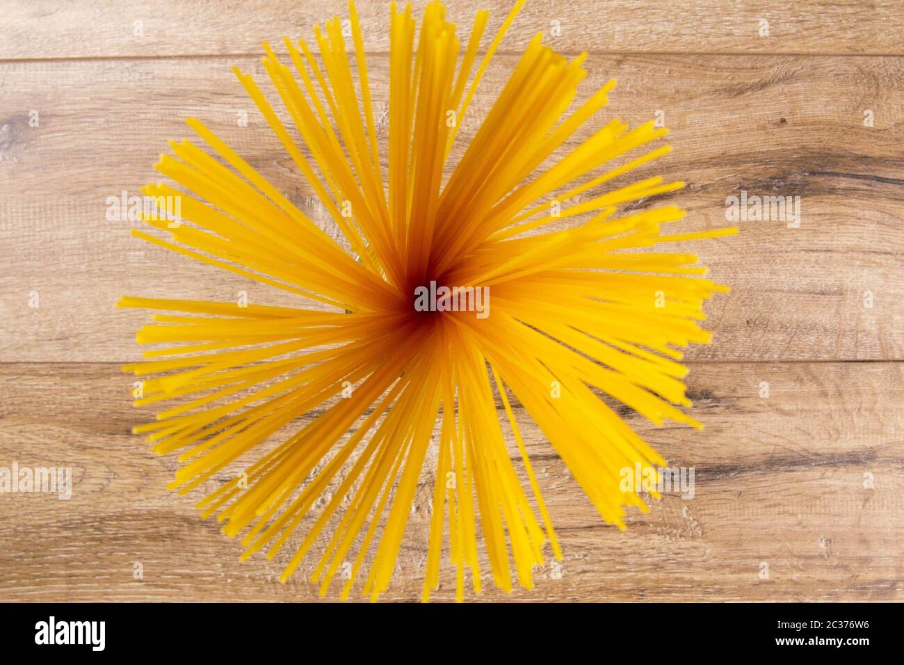 Raw spaghetti pasta inside a bowl on top of a wooden table and ...