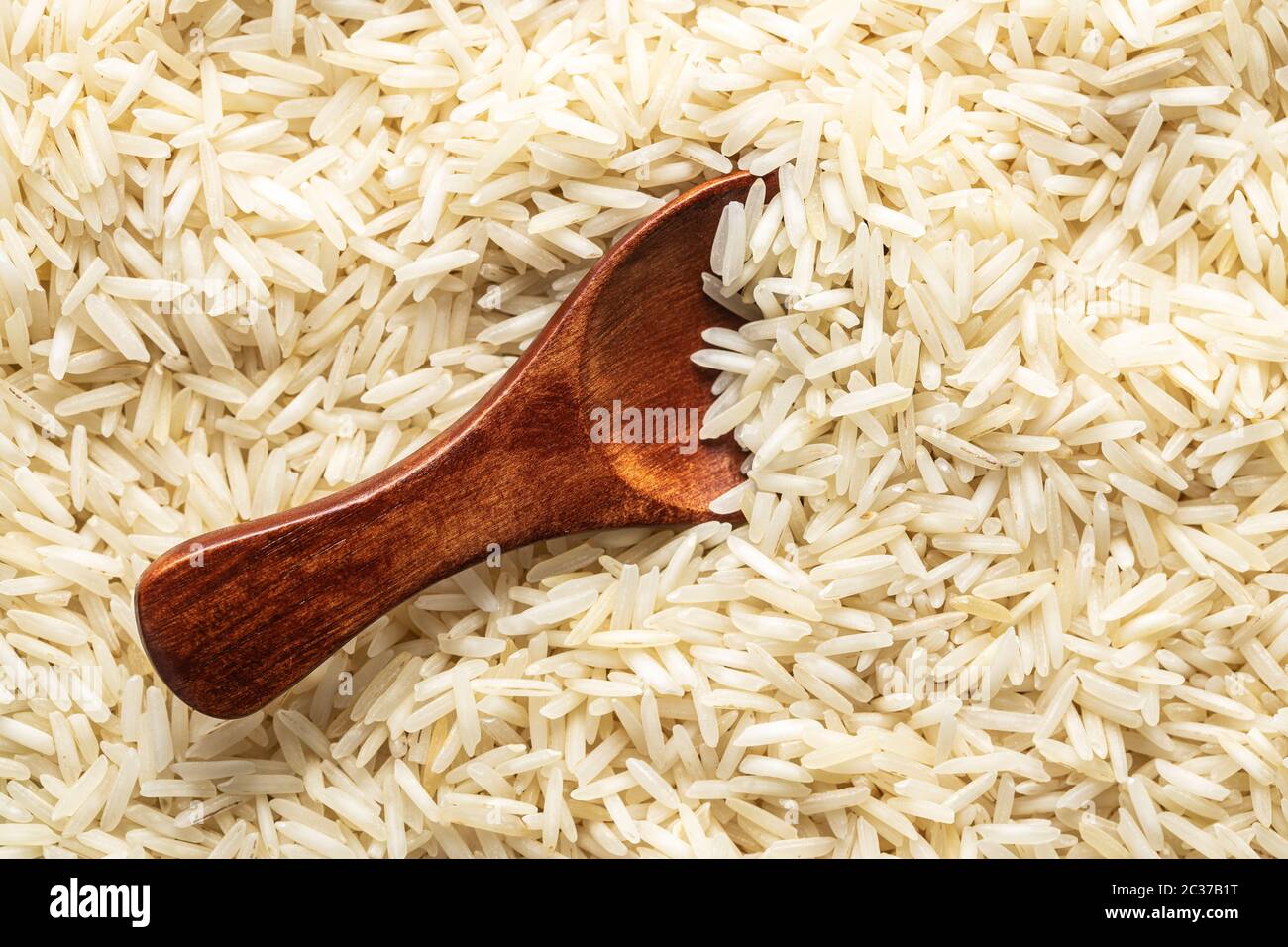 Uncooked indian long rice and wooden spoon. Top view Stock Photo - Alamy