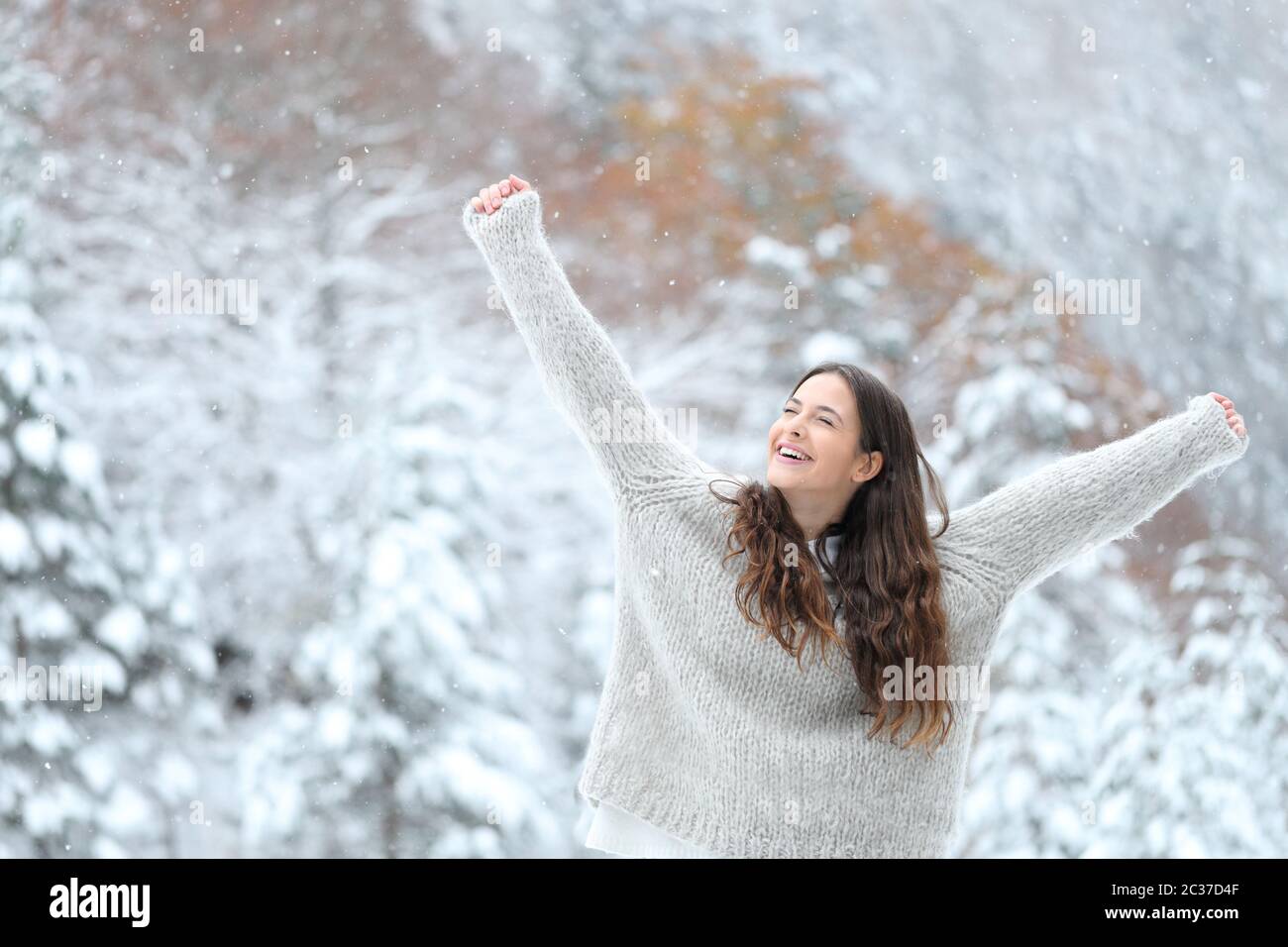 Excited girl raising arms enjoying snow in winter in the mountain Stock ...