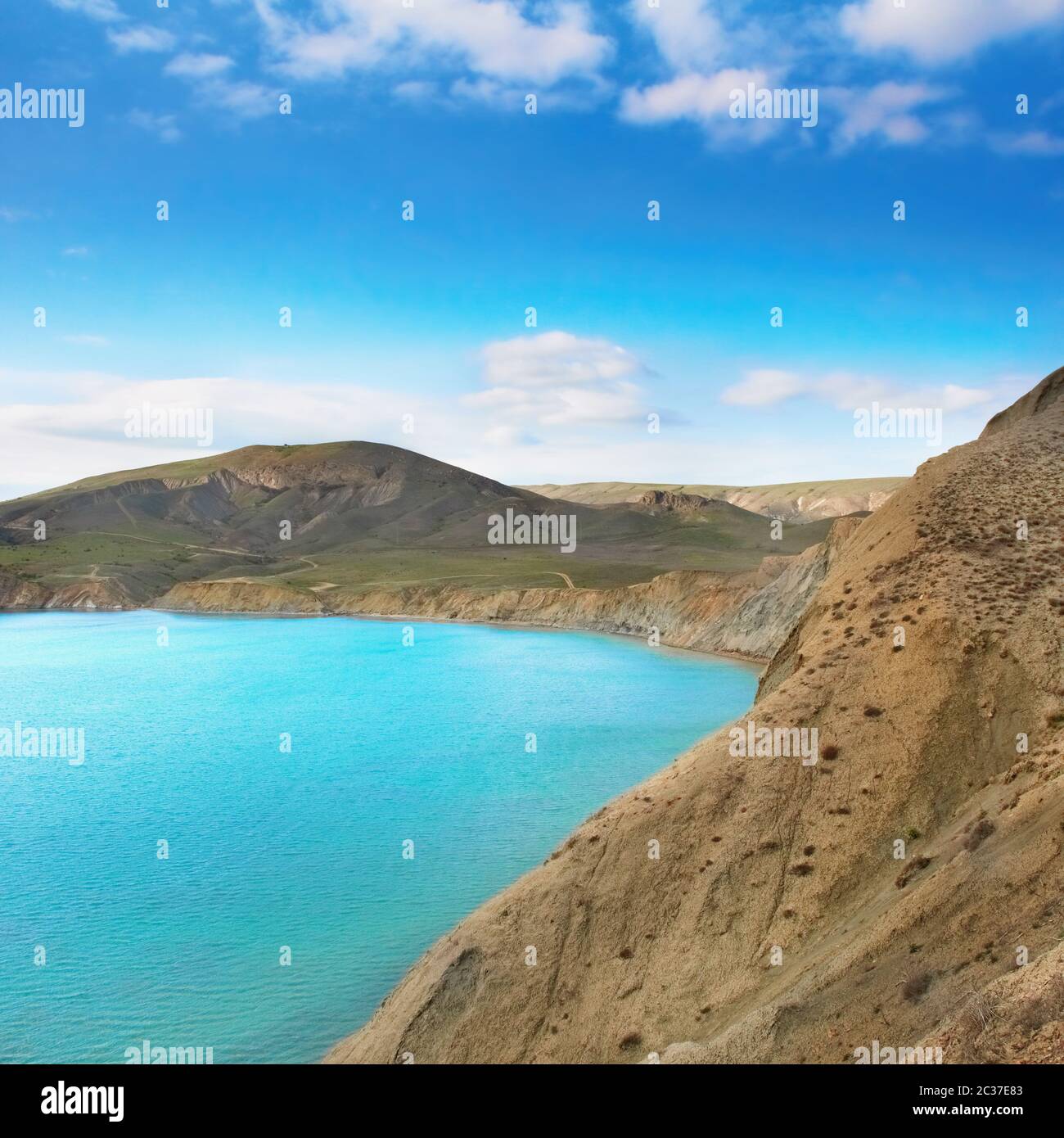 Sea harbor with blue water, green field and blue sky with clouds Stock Photo - Alamy