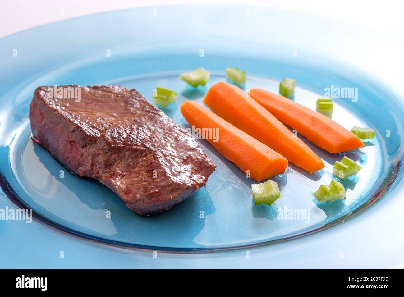 Roasted ostrich meat with carrots and celery on blue glass plate Stock ...