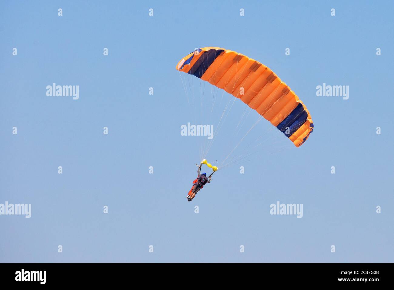 Instructor with student under the canopy of a parachute in blue sky ...