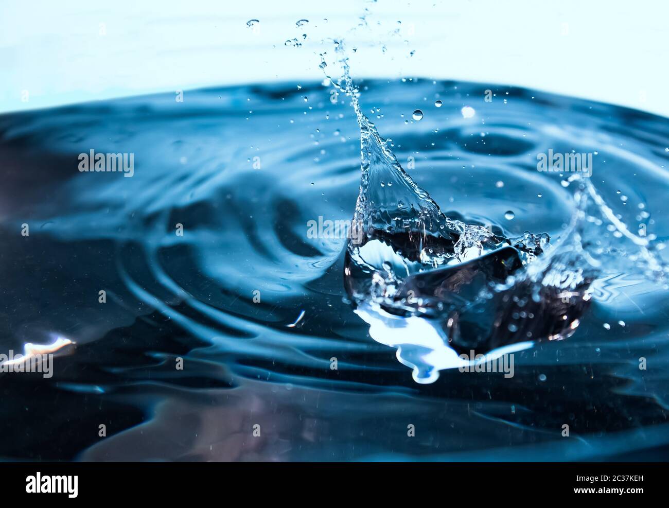 Water splash. Ice cubes falling into the blue water. Splash of ice ...