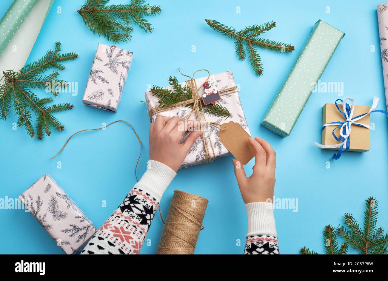 gift wrapped in pink paper and tied with a brown rope, two female hands ...