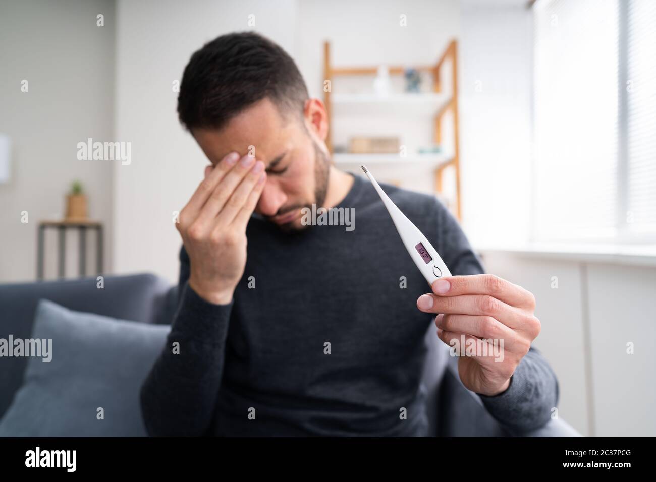 Sick Man Holding With Fever Holding Thermometer Showing High ...