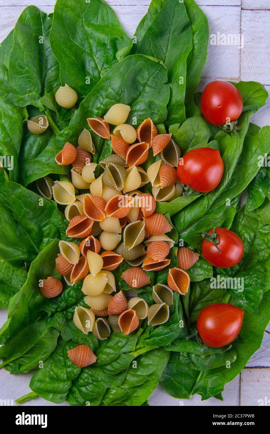 Raw conchiglie pasta with spinach and tomato. Italian Cuisine. Vegan ...