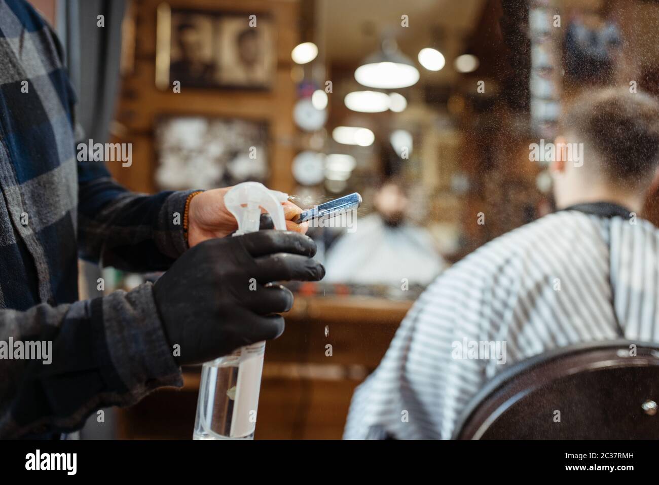 Barber processes the blade with spray, customer sitting in chair ...