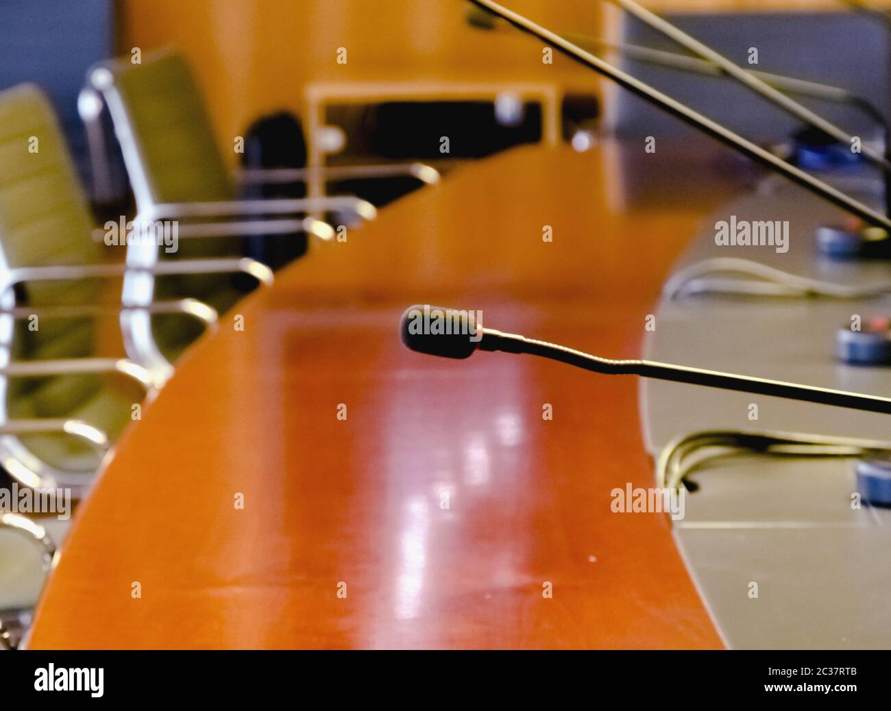a table microphone in a board room with a wooden table and a row of ...