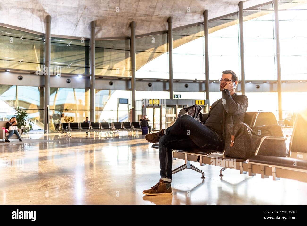 Casual young man talking on cell phone while waiting to board a plane ...