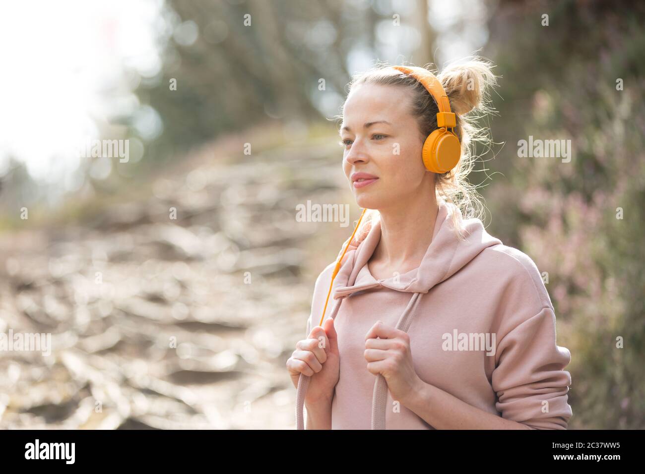 Portrait of beautiful sports woman with hoodie and headphones during ...