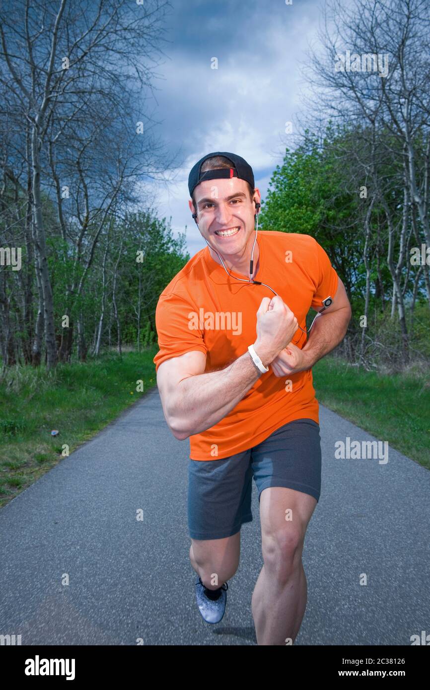 Frontal full body view of a running athlete in an orange shirt in a ...