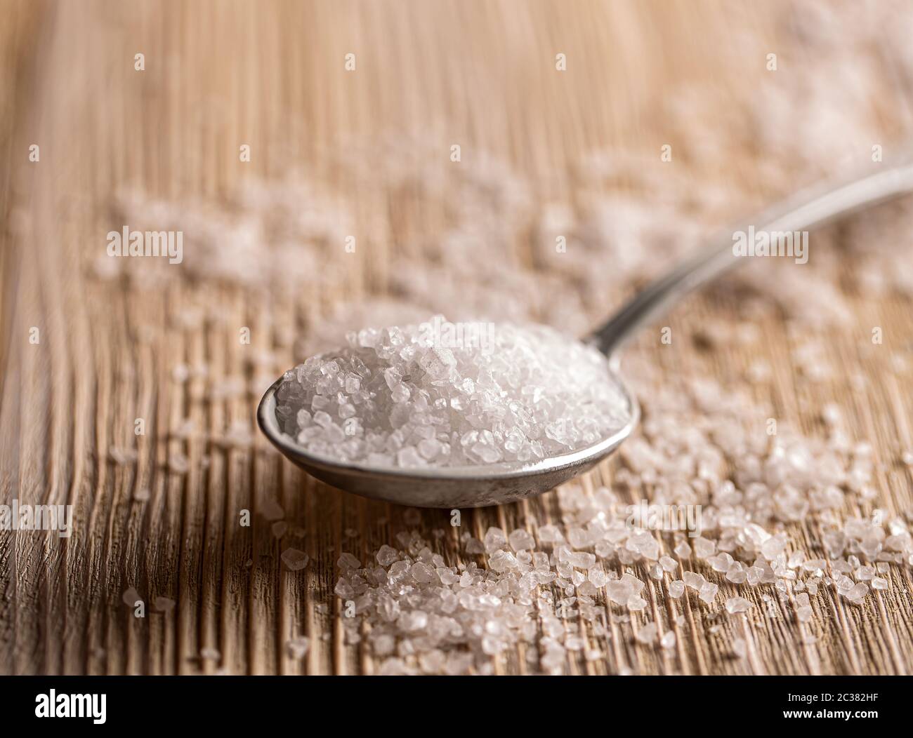Granulate sea salt in spoon on wooden background Stock Photo - Alamy