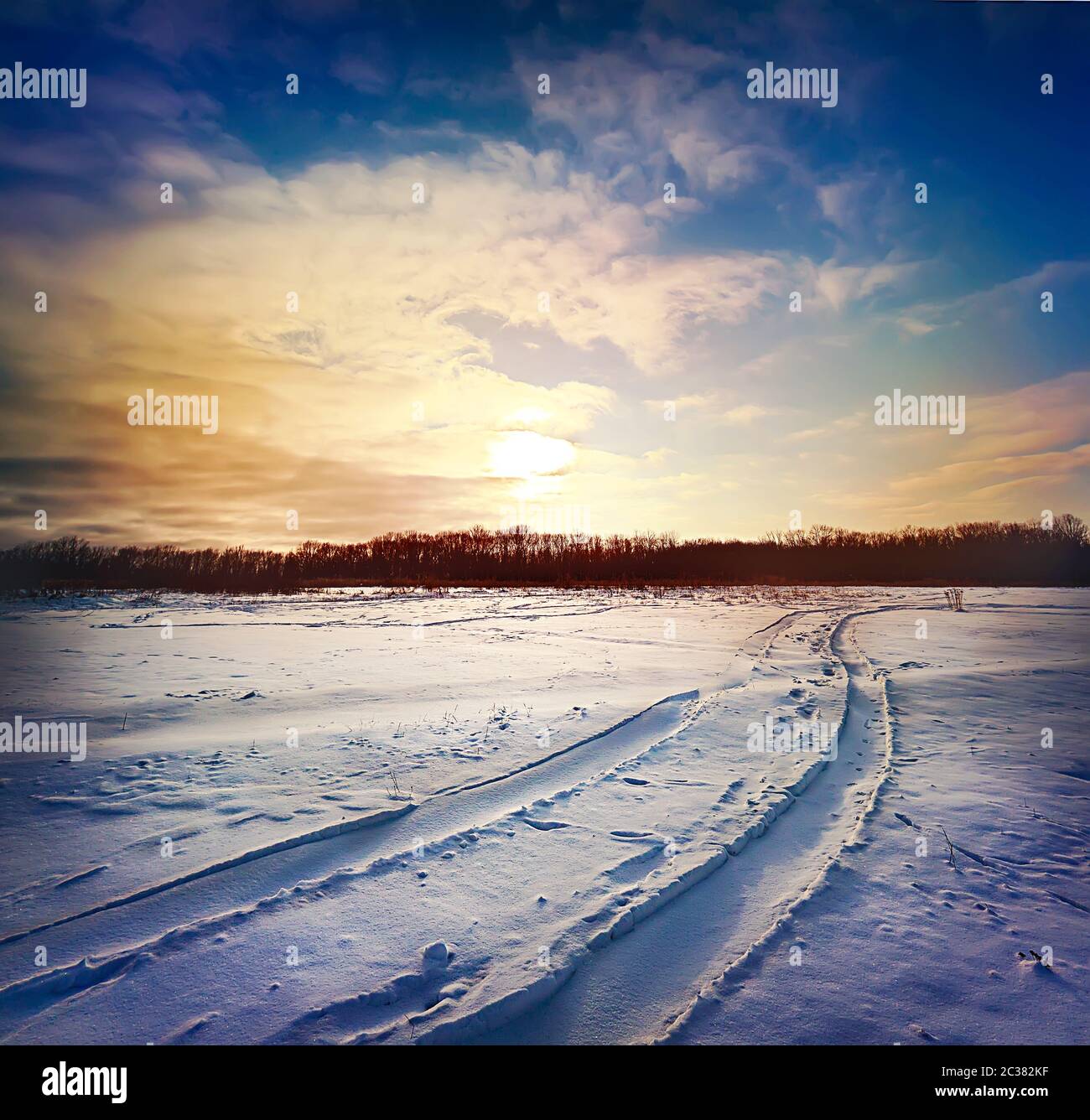 Road through snowy field under dramatic sunset sky Stock Photo - Alamy