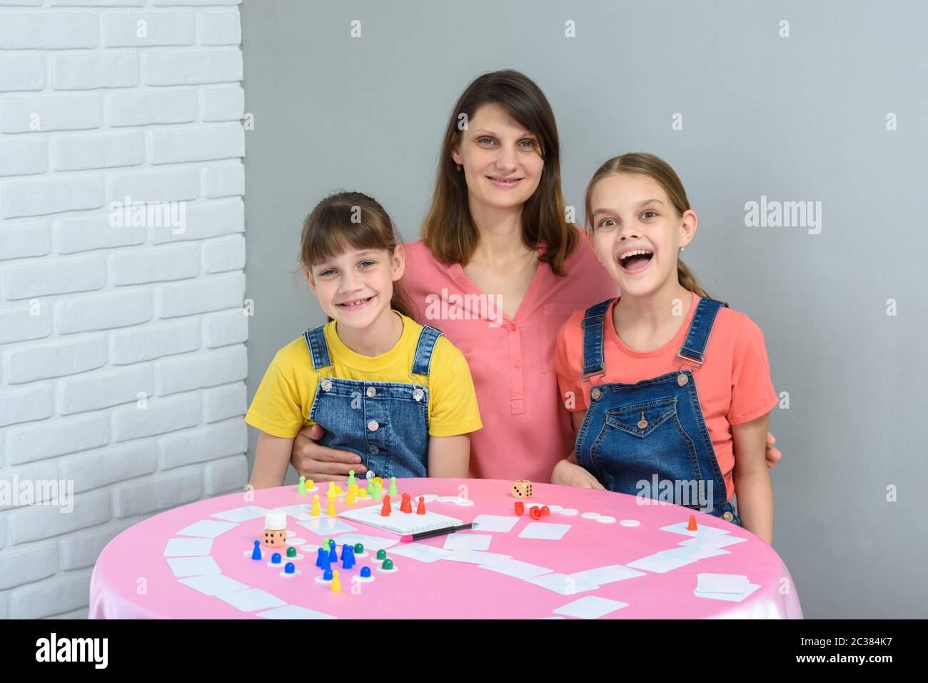 Happy family having fun laughing while playing board games at a table ...