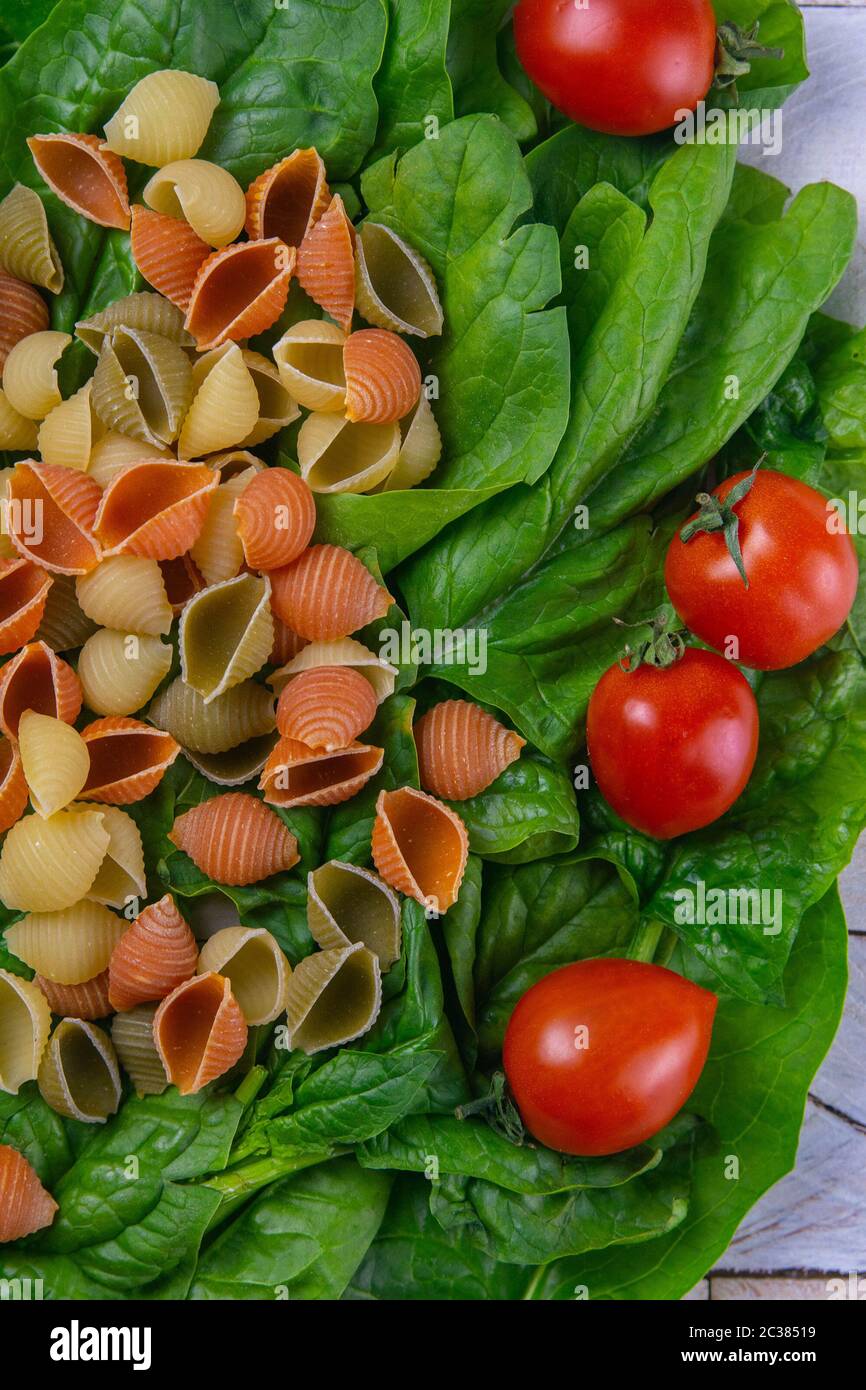 Raw conchiglie pasta with spinach and tomato. Italian Cuisine. Vegan ...