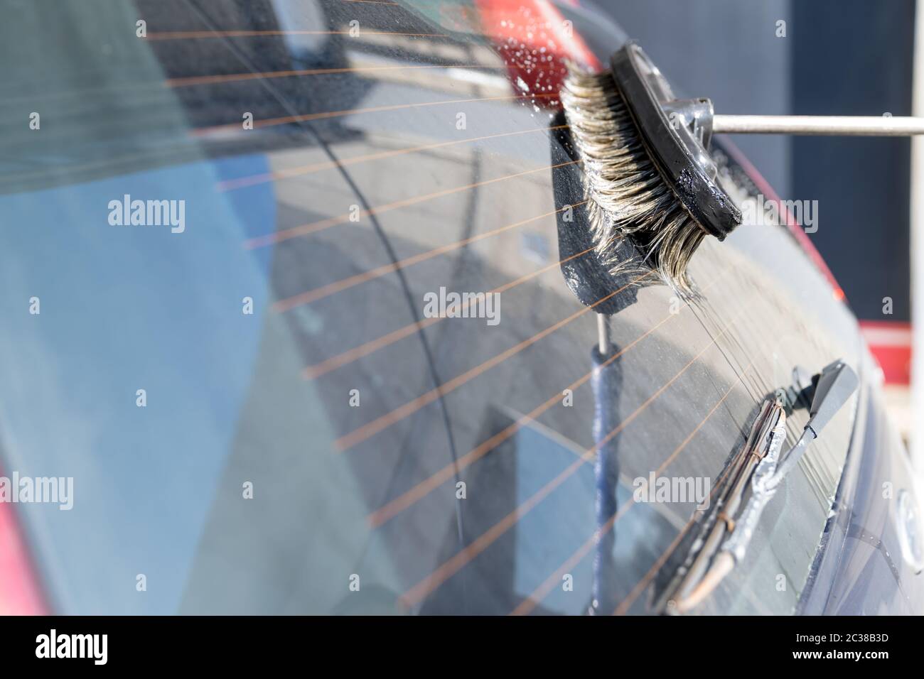 hand wash the rear window of the car using brush and water with shampoo ...