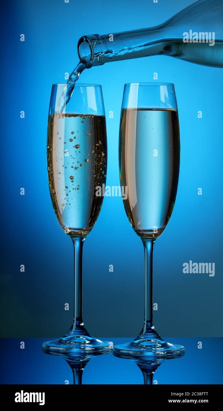The aromatic champagne from the bottle is poured into two glasses on a ...