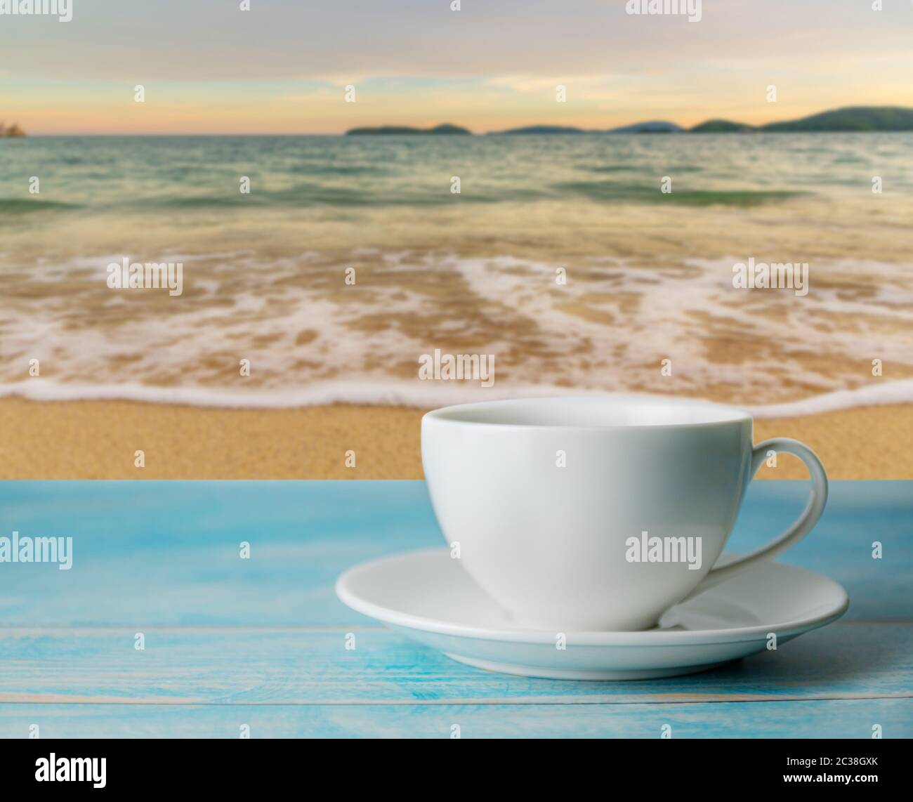A cup of coffee with blurred beach sunset or sunrise and colorful of ...