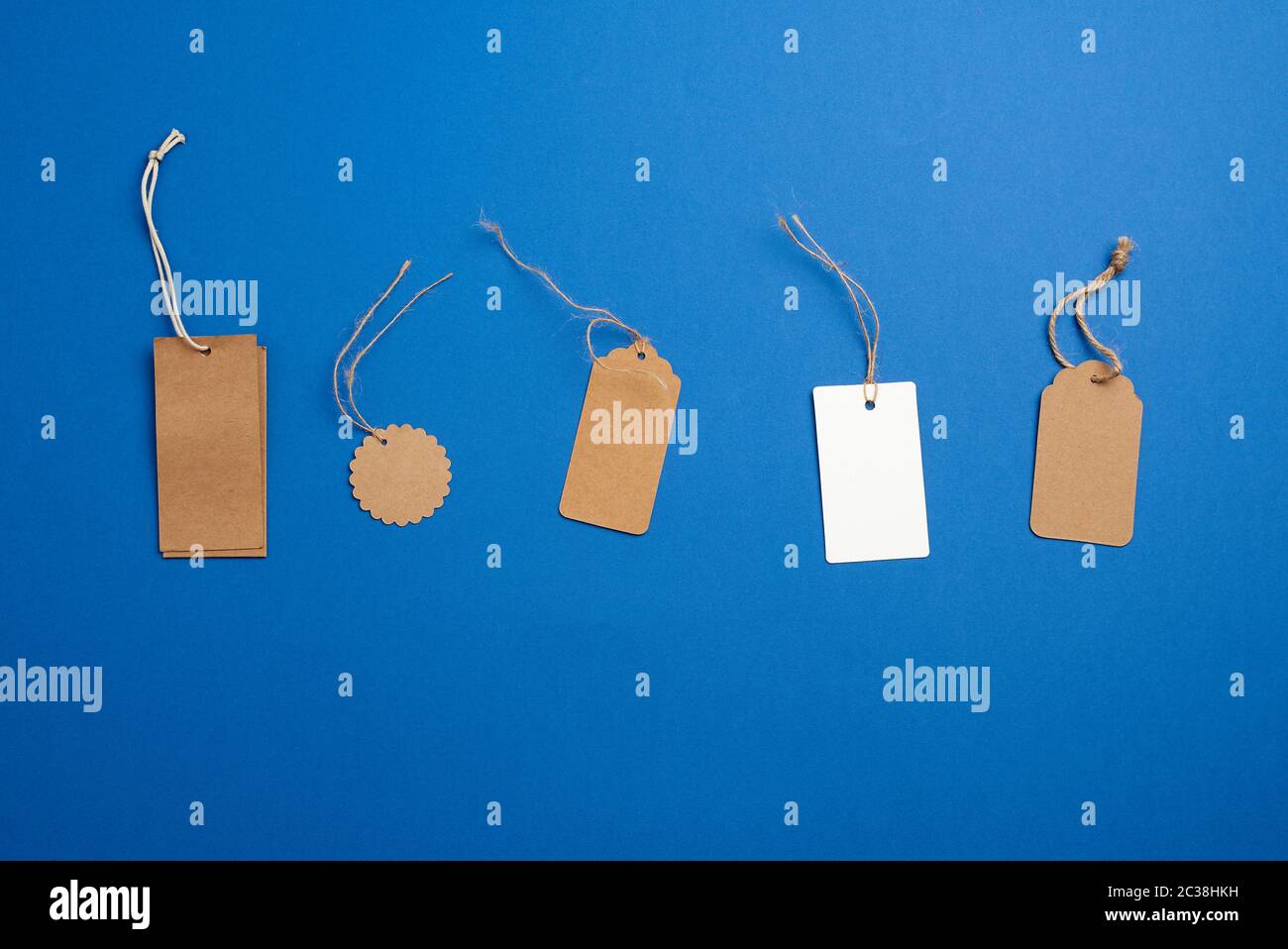 set of paper brown and white blank tags on a rope on a blue background ...