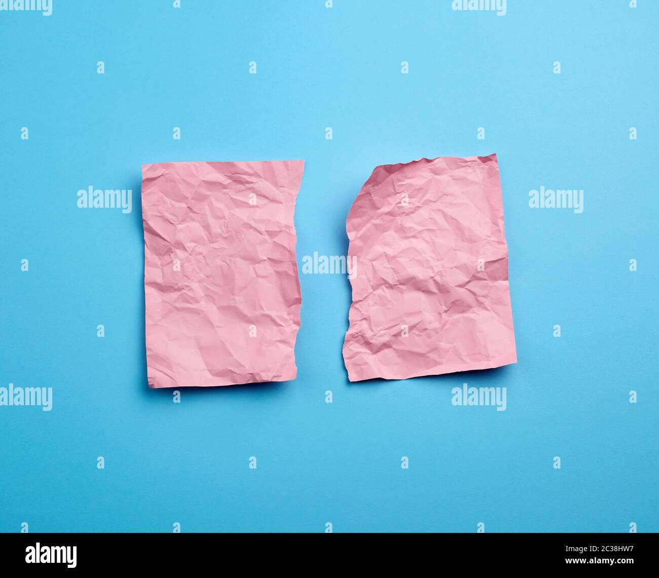crumpled pink sheet of paper torn in two on a blue background. Paper ...