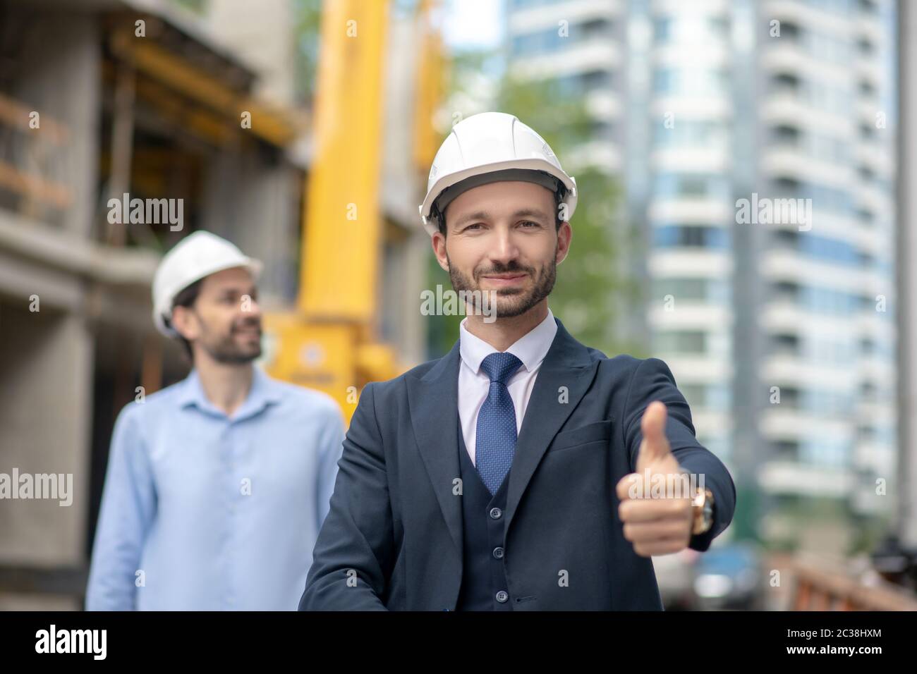Building site. Building supervisor showing thumb up, foreman standing ...