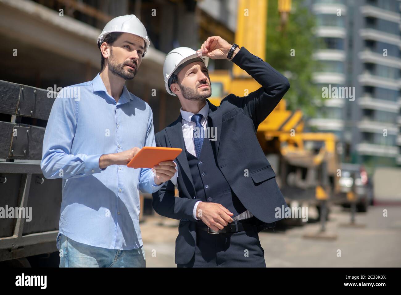 Building site. Foreman holding tablet, discussing something with ...