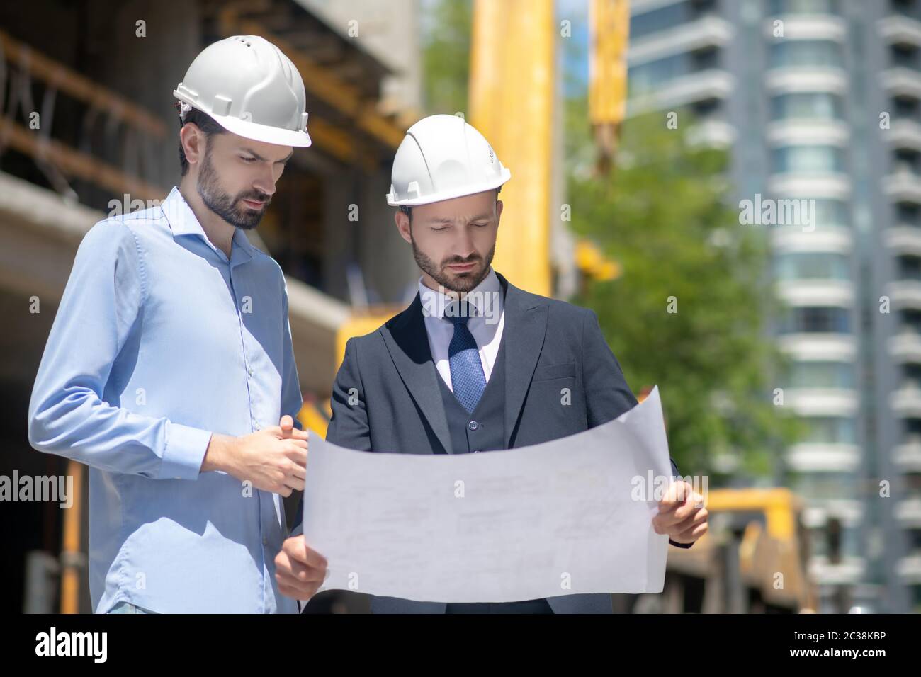 Building site. Foreman and building supervisor holding blueprint ...