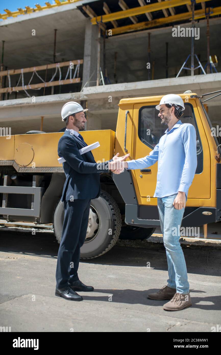 Building site. Building supervisor and foreman greeting, shaking hands ...
