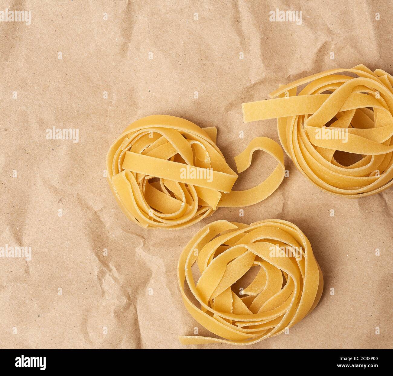 twisted pasta in round fettuccine nests on brown paper, top view Stock ...