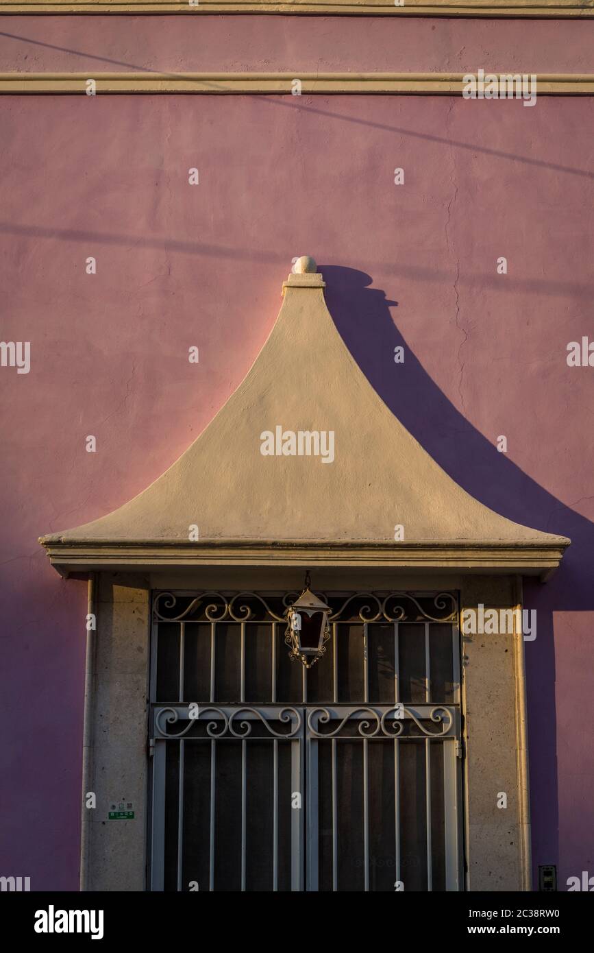Detail of a sunlit facade with a stick triangular pediment over a ...