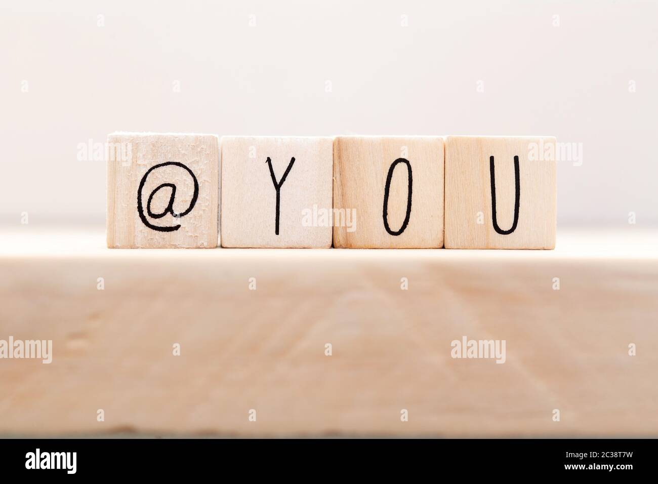 Wooden cube signs with At sign and the word you on white background ...