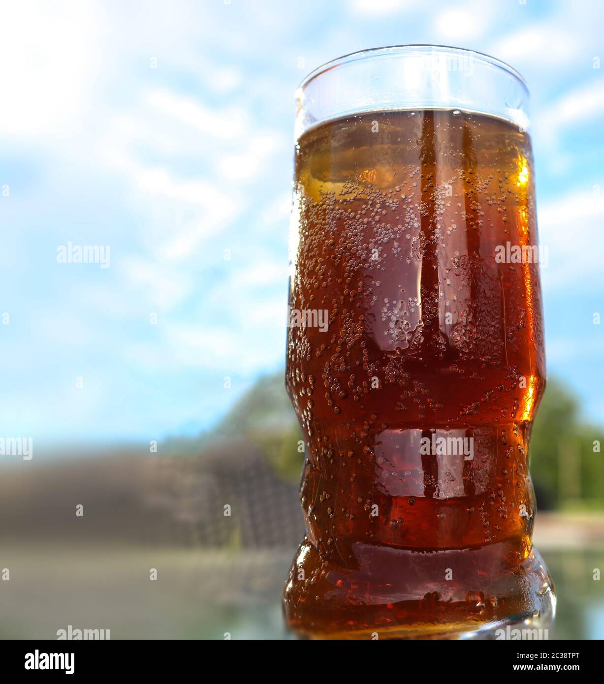 Refreshing orange summer cocktails with cola and ice against a blue sky ...