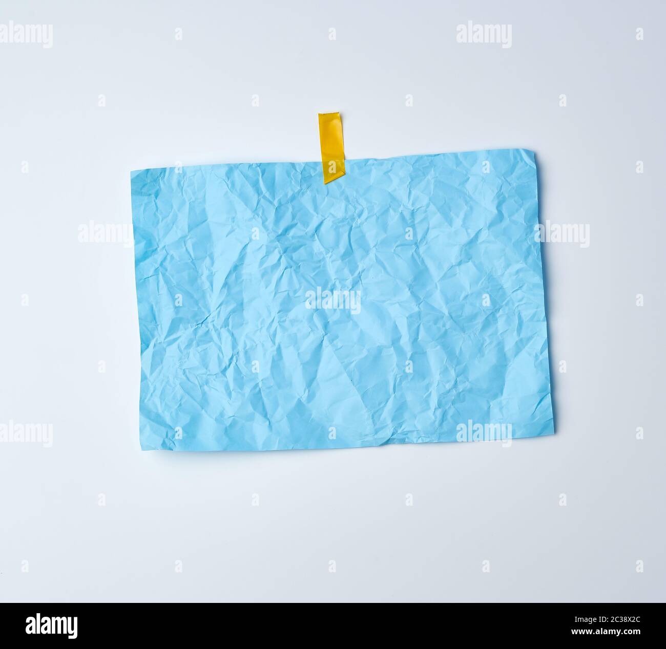 blue crumpled sheet of paper glued with adhesive tape on a white ...