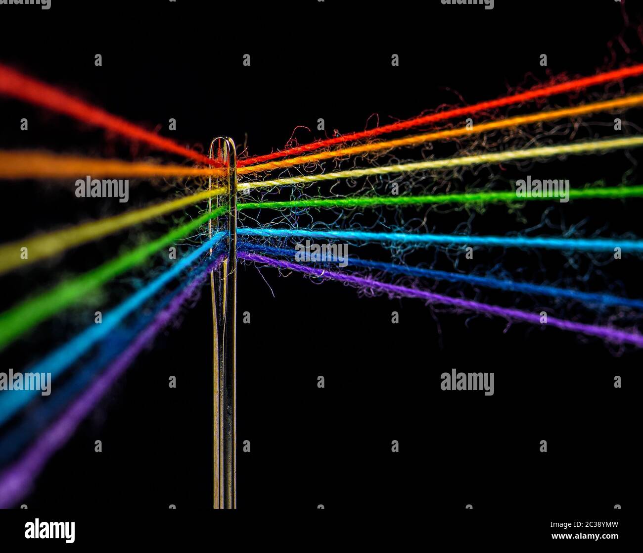 Multicolored threads, forming the colors of the rainbow, are threaded ...