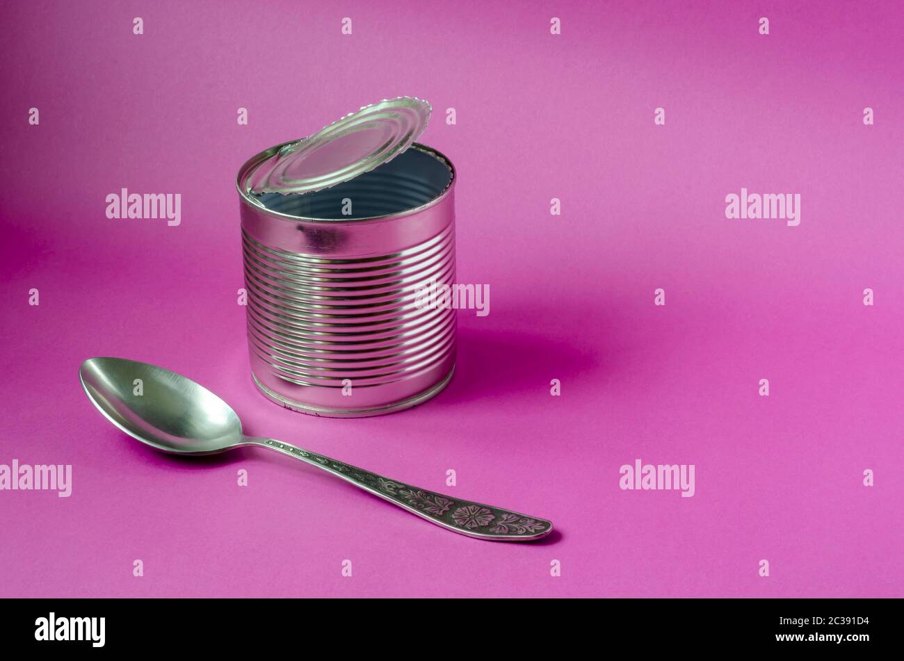 Empty tin can and spoon on a purple background. Tin can and metal spoon ...