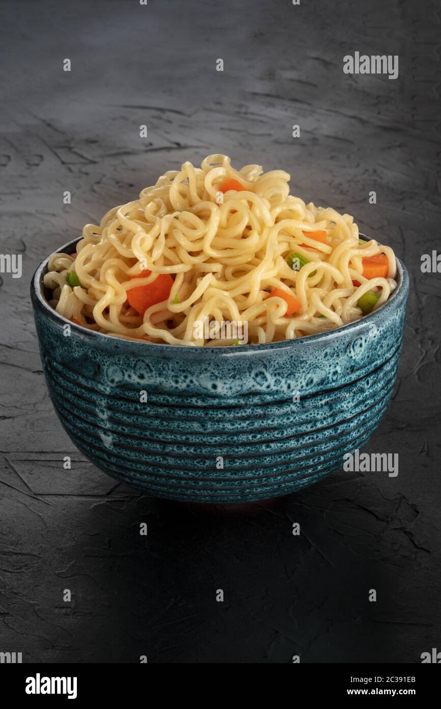 Instant noodles with carrot and scallions, on a black background with a ...