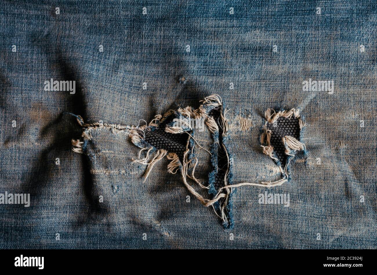 Old ripped jeans background. A detailed shot of a fragment of denim ...