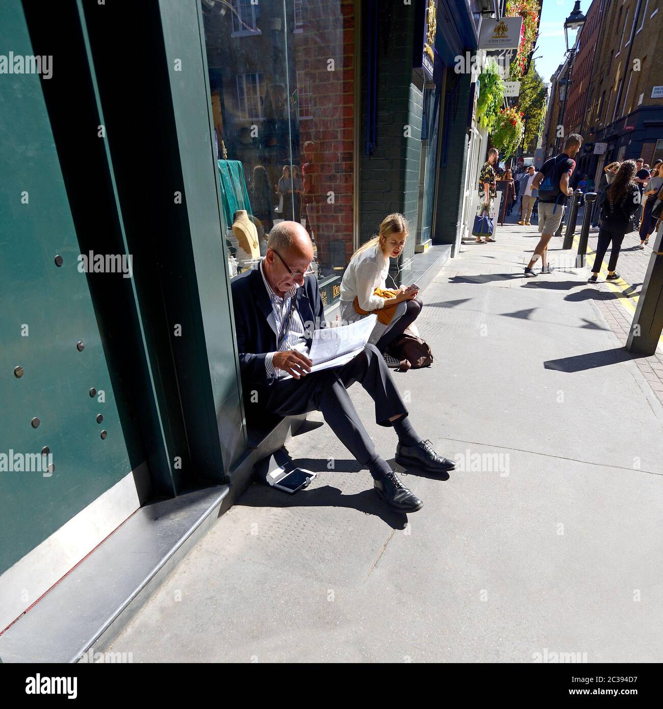 London, England, UK. Man and young woman stitting n the pavement ...