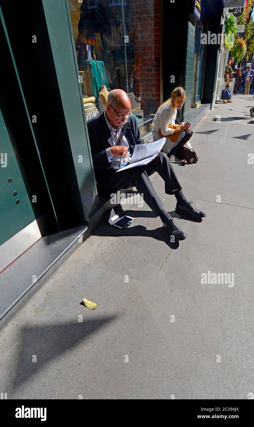 London, England, UK. Man and young woman stitting n the pavement ...