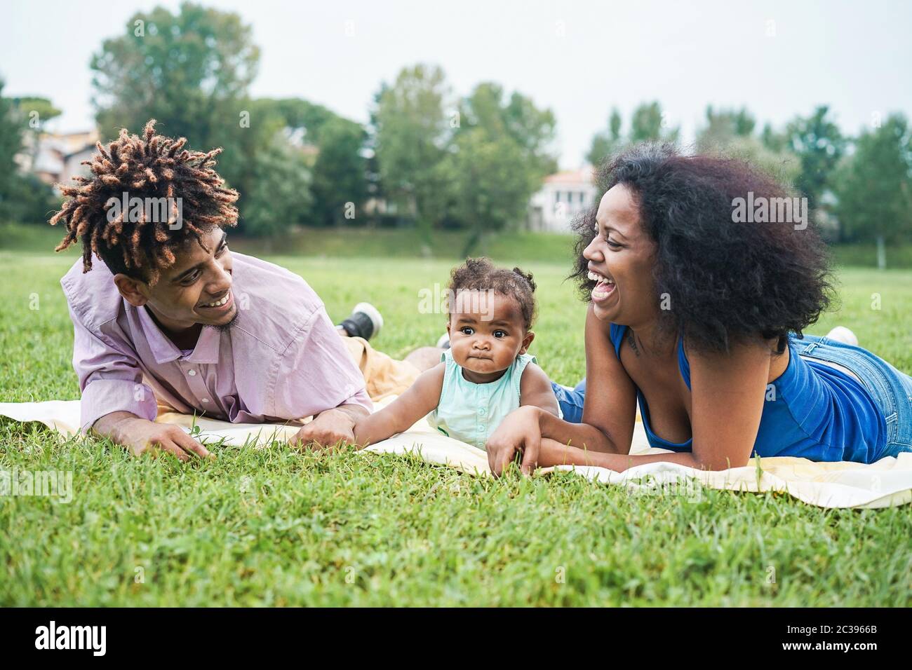 Happy black family having fun sitting on grass outdoor - Parents and ...
