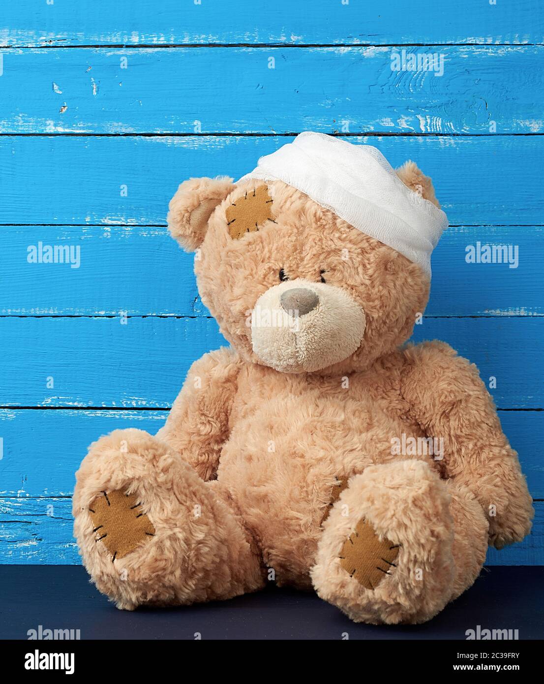 sad brown bear sits with bandaged white medical bandage head, injury ...