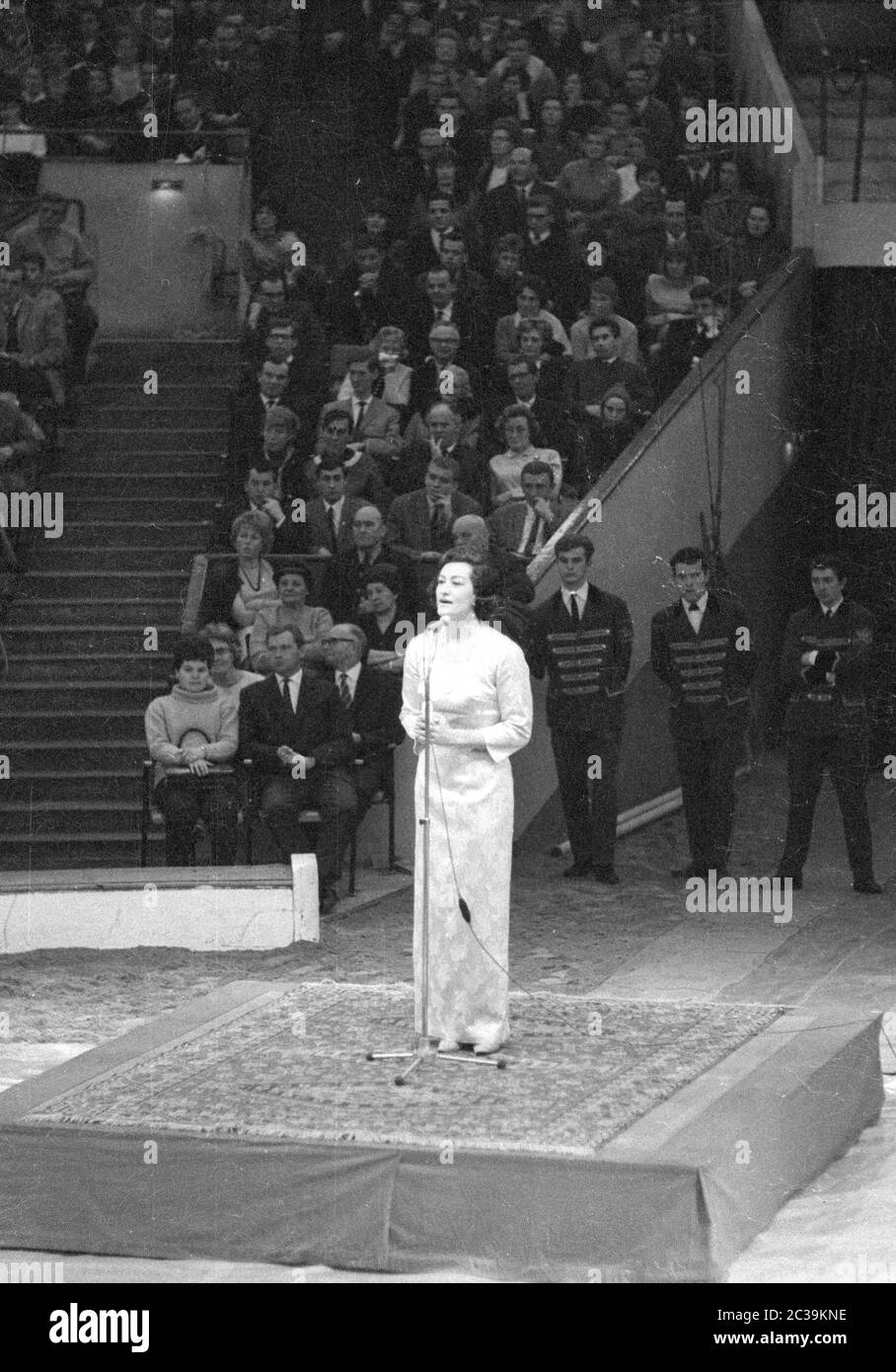 A woman speaks to the audience through a microphone in the circus ring ...