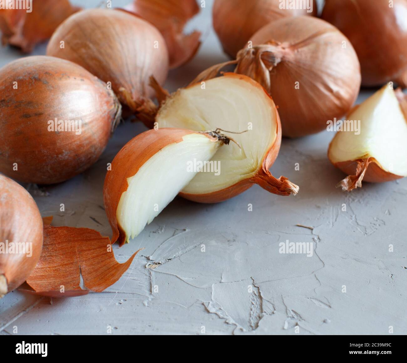 Raw yellow onions on a grey board close up Stock Photo - Alamy