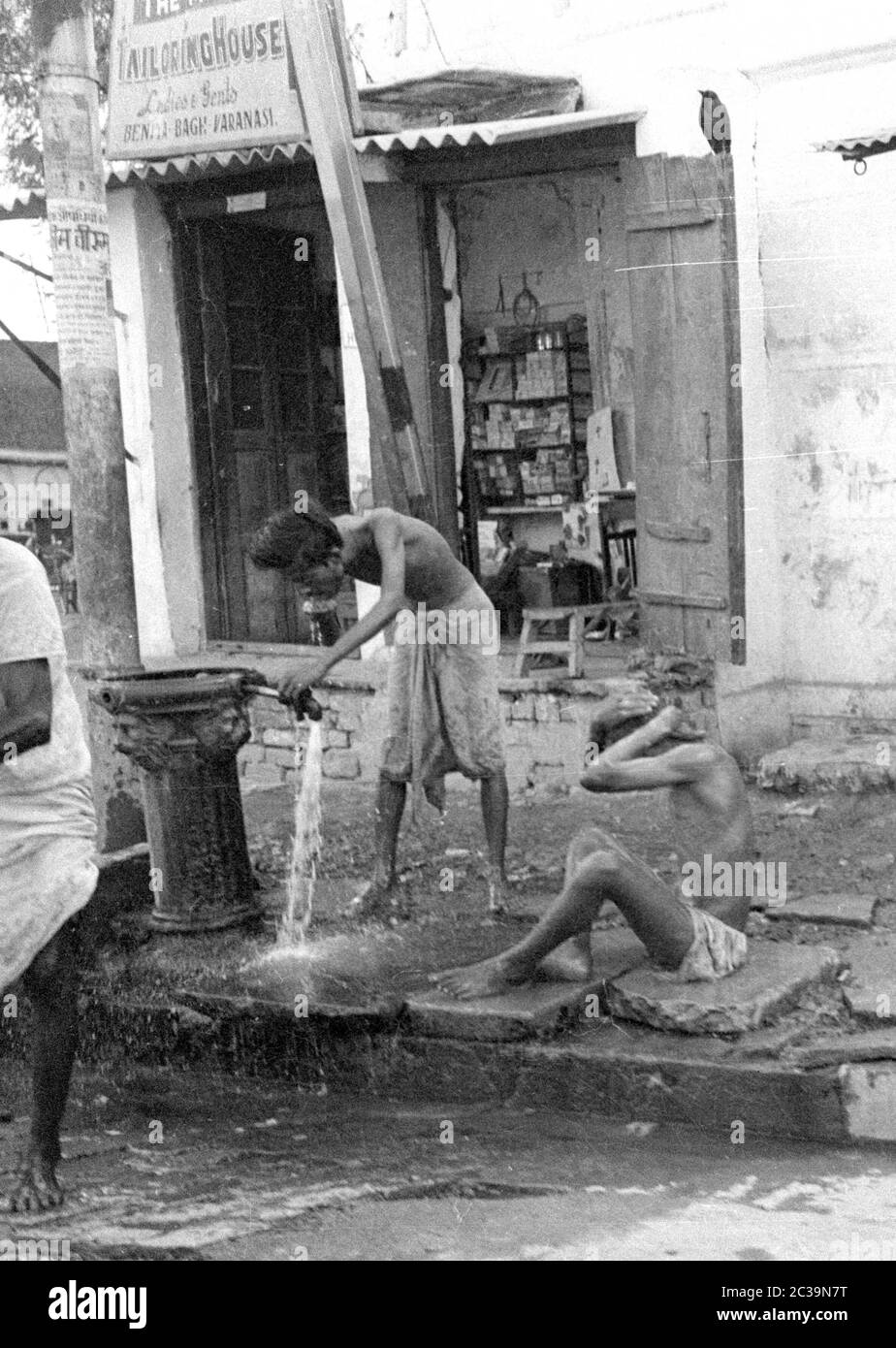 Two young Indian men at a drinking water well in a poor district of ...