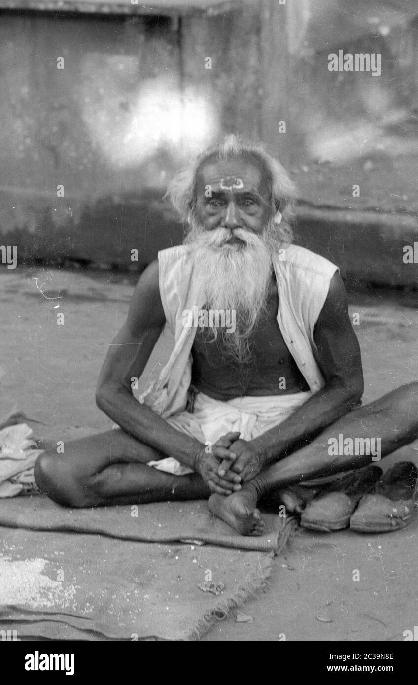 An ascetic-looking man, possibly a Hindu priest, sitting on the ground ...
