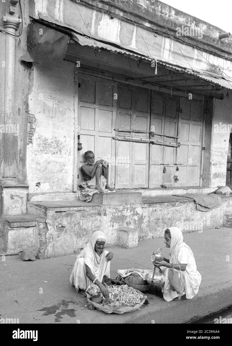 Two old women are eating at the roadside, in a traditional way, sitting ...